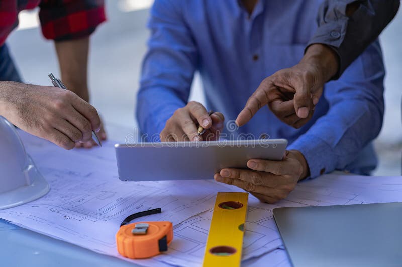 Engineer Pointing at Blueprint and Using Laptop To Draw Project Design ...