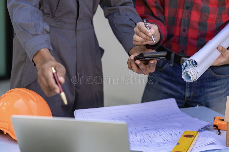 Engineer Pointing at Blueprint and Using Laptop To Draw Project Design ...
