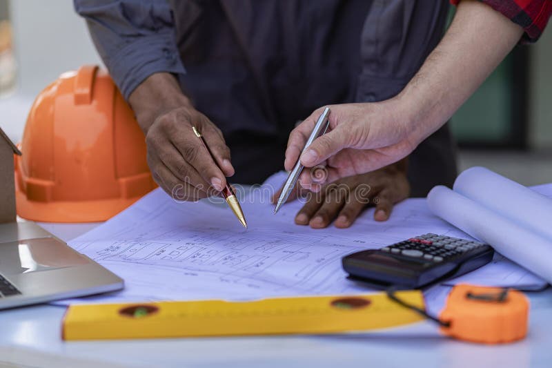 Engineer Pointing at Blueprint and Using Laptop To Draw Project Design ...
