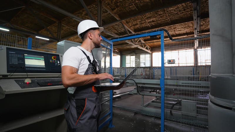Engineer Programmer with Laptop on Industrial Factory Analyzes the ...