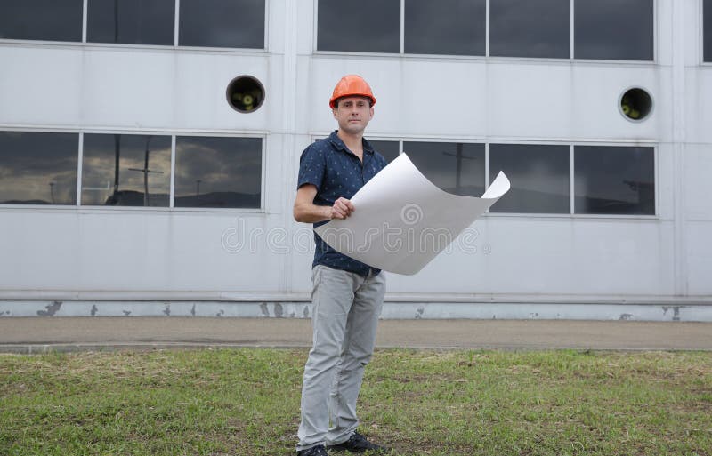 Engineer in a Protective Helmet with Blueprints in Front of the ...