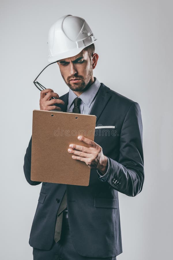 Engineer Reading Clipboard and Scratching Temple Stock Photo - Image of ...