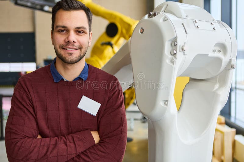Engineer Smiling Near Robot Arm in High-tech Industrial Environment ...