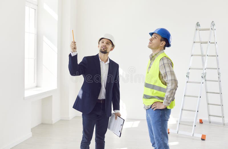Engineer Standing with Foreman in Room, Pointing at Something ...
