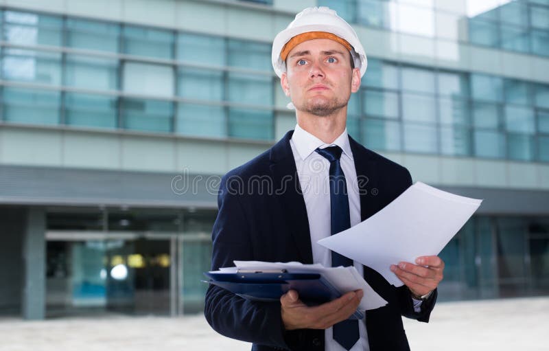 Engineer in Suit and Hat with Folder is Looking into Documents with ...