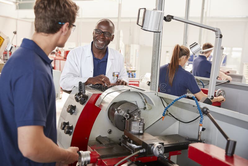 Engineer Talking To Male Apprentice at His Workstation Stock Photo ...