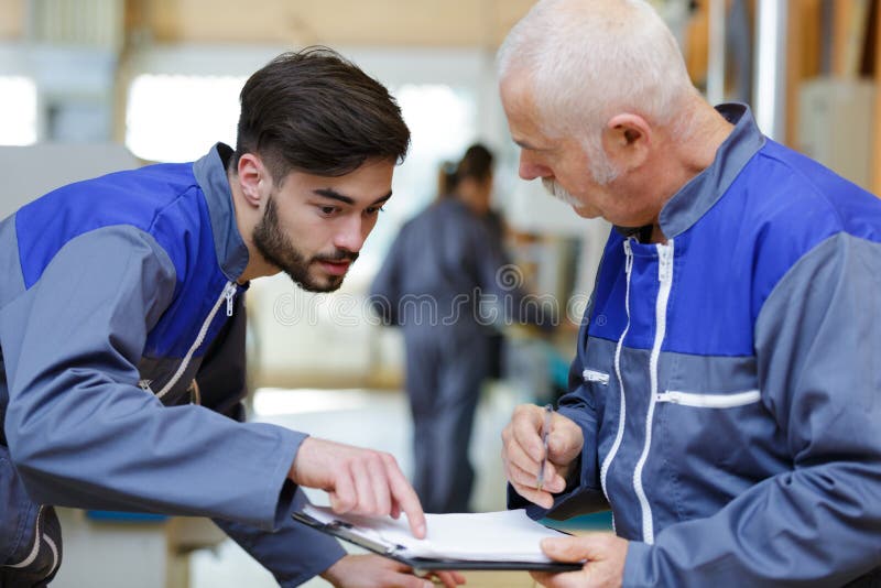 Engineer Talking To Male Apprentice at Workstation Stock Photo - Image ...