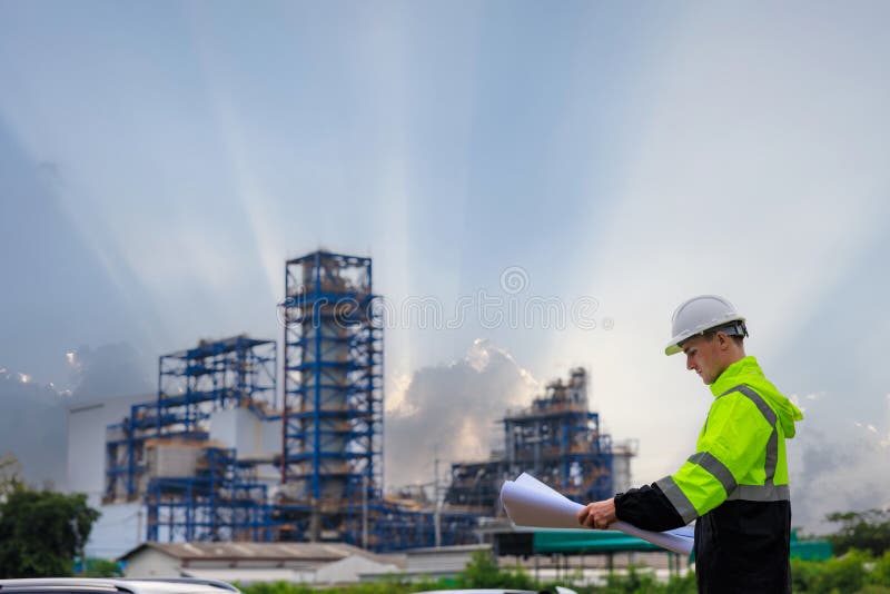 Engineer in Uniform and Hardhat Stood Looking Down at Blueprint at Oil ...