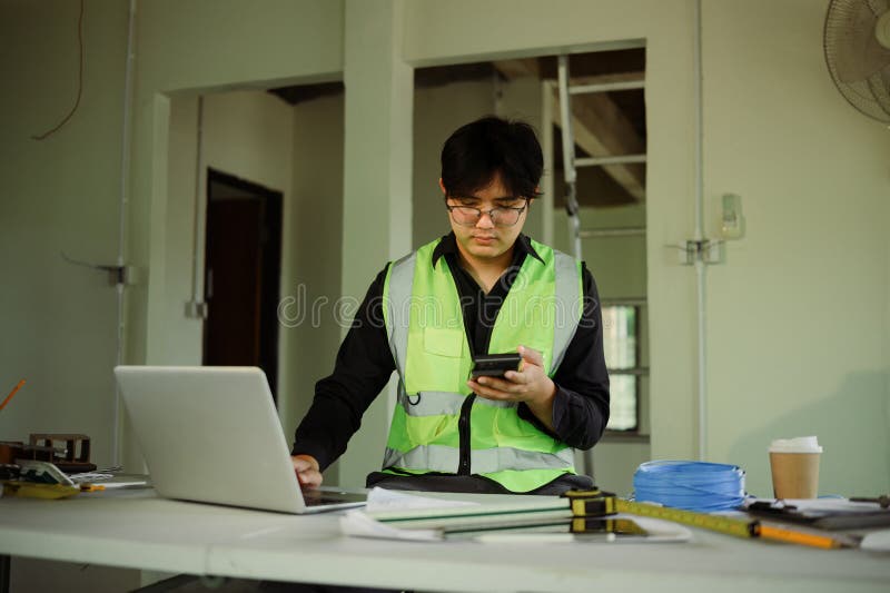Engineer Using Smartphone at Construction Planning Desk with Tools and ...