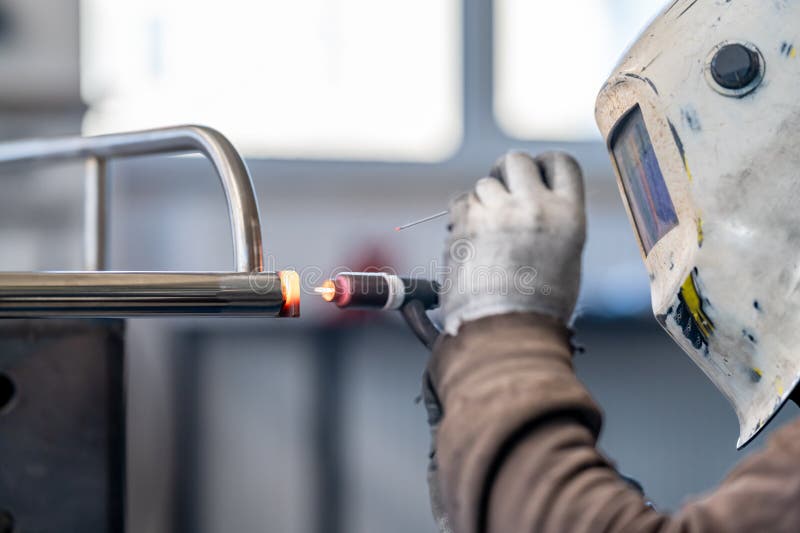 A Man Wearing a Welding Helmet is Using a Welding Machine To Weld a ...