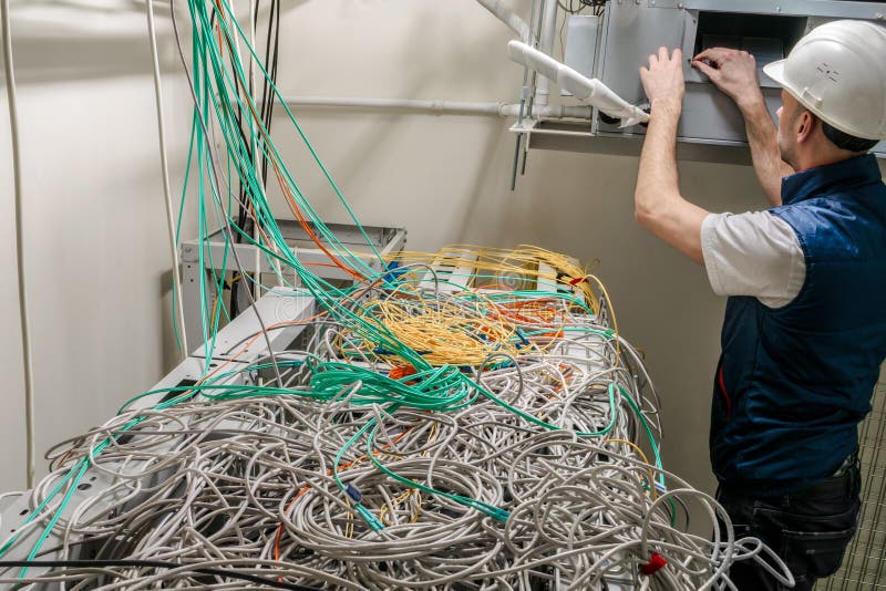 A Technician Connects a Fiber Optic Internet Cable in a Server Room. a ...