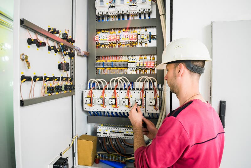 An Engineer in a White Helmet Works in an Electrical Box. the ...