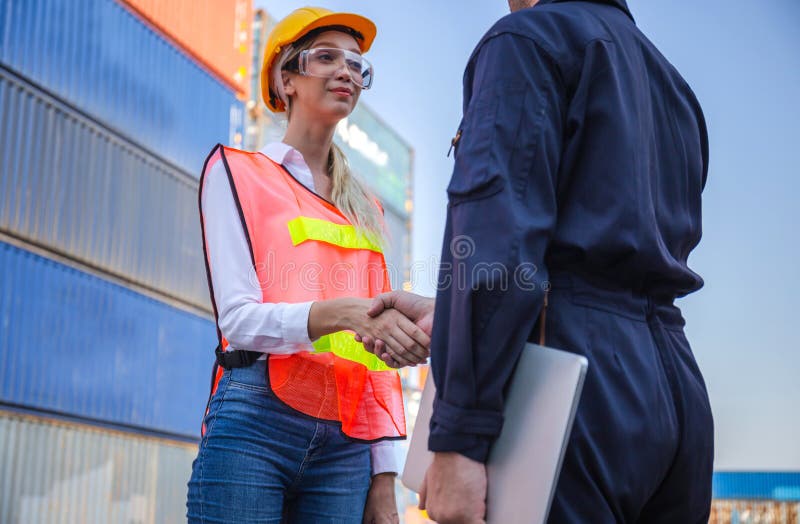 Engineer and Worker Handshake with Blurred Containers Cargo Background ...