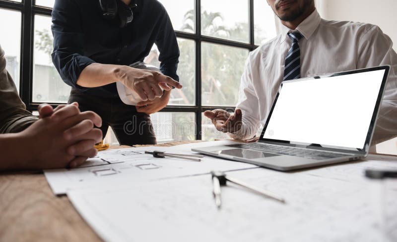 Engineering Team Collaborating on Work Plans Around a Table with Laptop ...