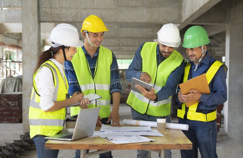 Engineering Teamwork Wearing Full Safety Gear Discussing with Blueprint ...