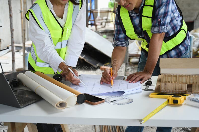 Engineers and Businessman Examining Blueprints at Table with ...