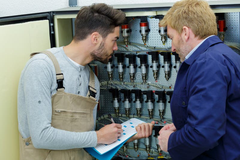 Engineers with Clipboard Checking Equipment in Cabinet Stock Photo ...