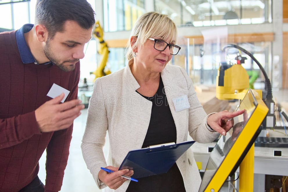 Engineers Discussing Automation Process in a Robotics Lab Setting with Touchscreen Interface ...