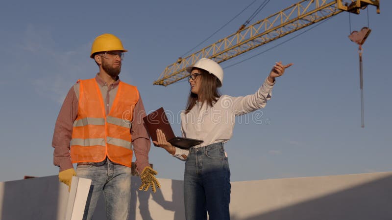 Engineers Discussing Blueprint on Construction Site with Crane and ...