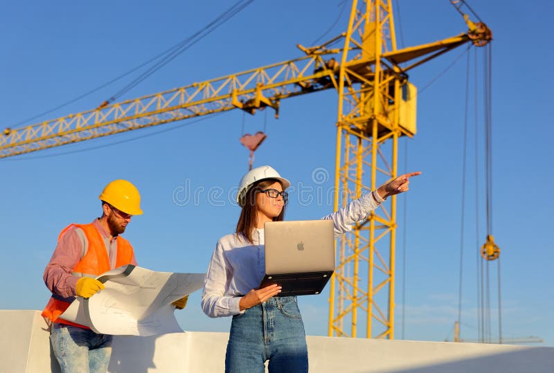 Engineers Discussing Blueprint on Construction Site with Crane and ...