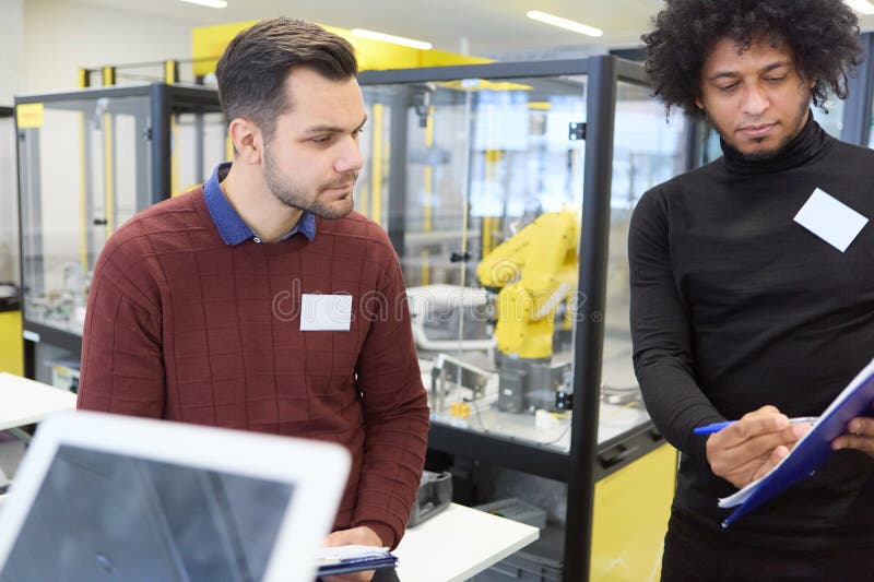 Engineers Discussing Robot Programming And Automation In Laboratory 2760