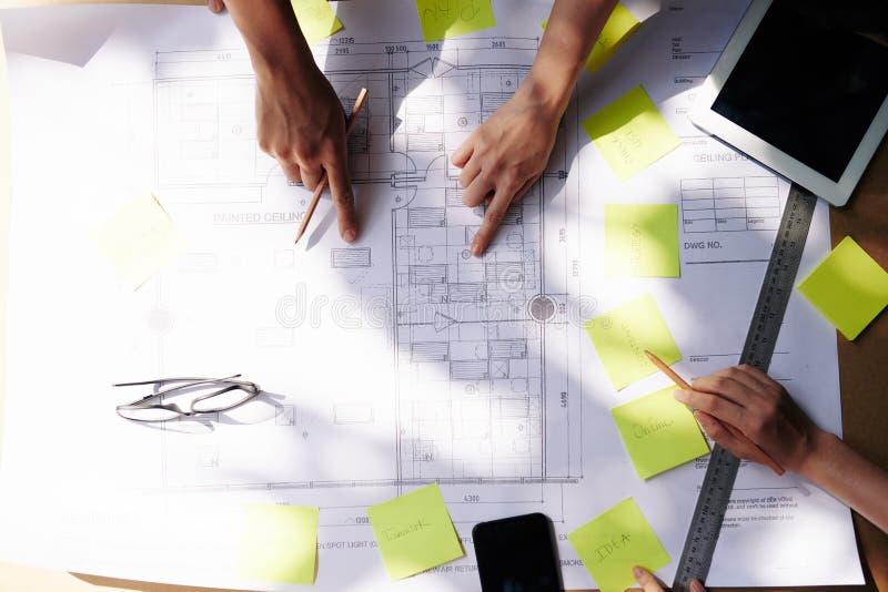 Engineers Pointing To Building on Blueprint and Using Laptop To Drawing ...