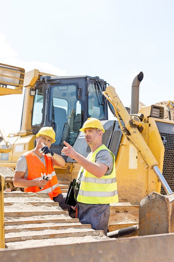 Engineers Pointing while Discussing at Construction Site Against Clear ...