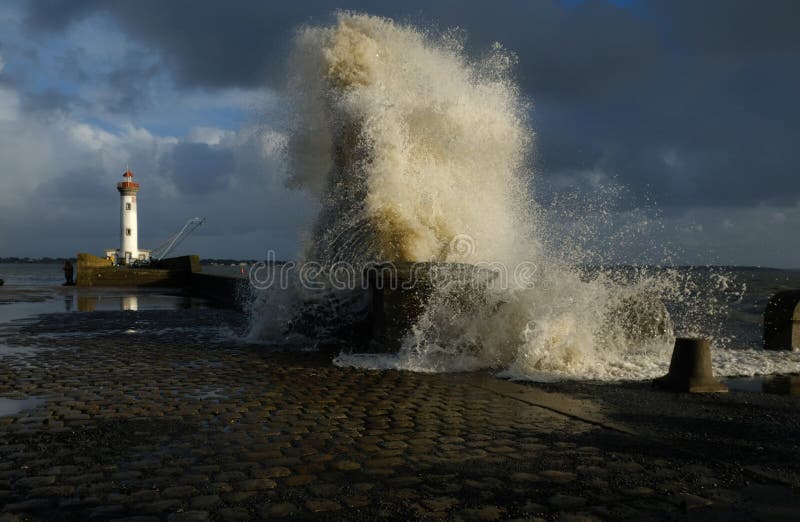 Enormous Splash of Water Next To a Lighthouse Under the Gloomy Sky ...