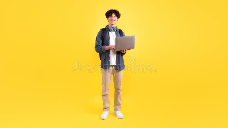 Enthusiastic Student Guy Using Laptop Computer Standing Over Yellow ...