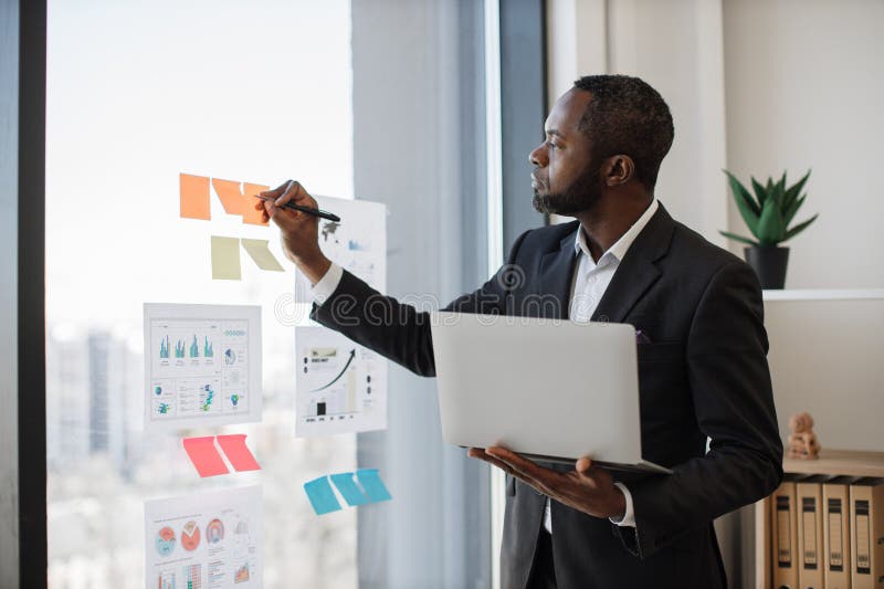 Entrepreneur Noting Down Details Using Laptop and Graphs Stock Photo ...