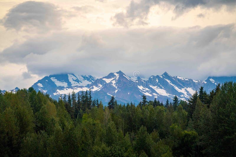 Epic Mountain Range with Peaks, Forest, and Clouds in Background of ...