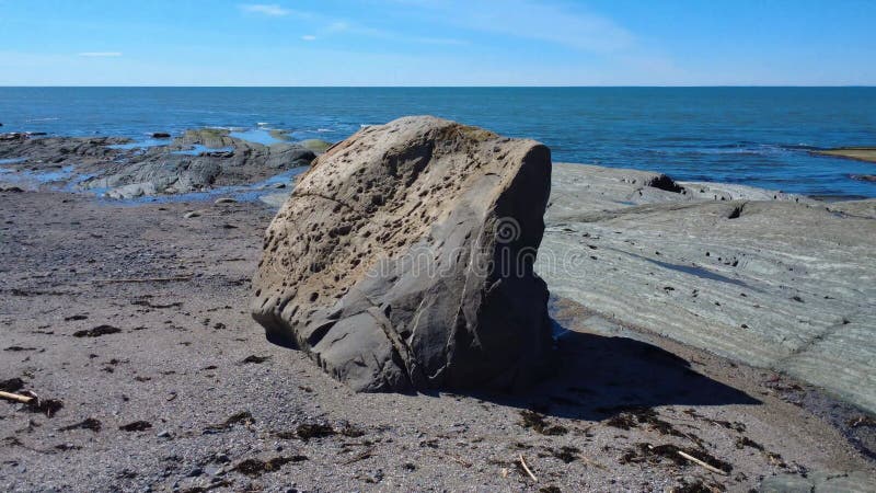 An Erratic Boulder Rests on a Sandy Beach in Front of an Outcrop of ...