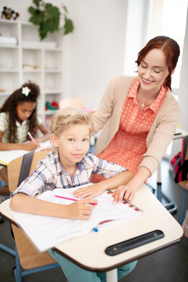 Escolar De Cabello Rubio Escuchando Al Profesor Y Anotando Foto de ...