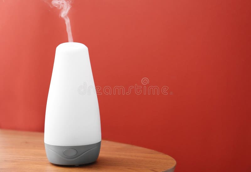 Essential Oils Diffuser on Wooden Table Near Red Wall Stock Photo ...