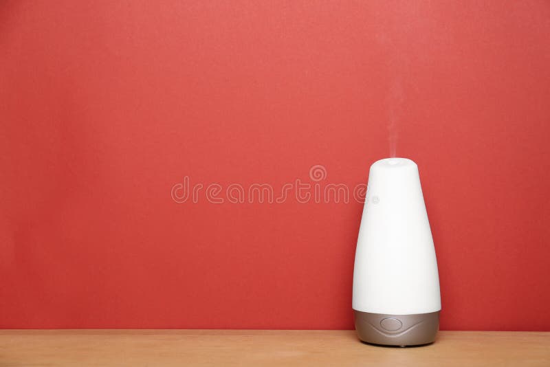 Essential Oils Diffuser on Wooden Table Near Red Wall Stock Photo ...