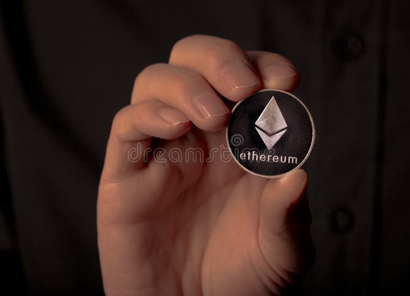 Ethereum Silver Crypto Coin in Male Hand Over Black Background. Eth or ...
