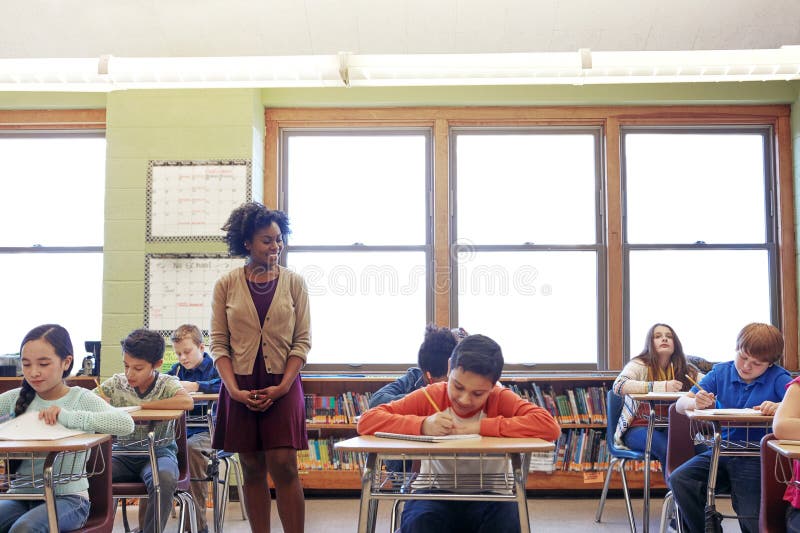 Evaluating Their Progress. a Teacher in a Classroom with Her Students ...