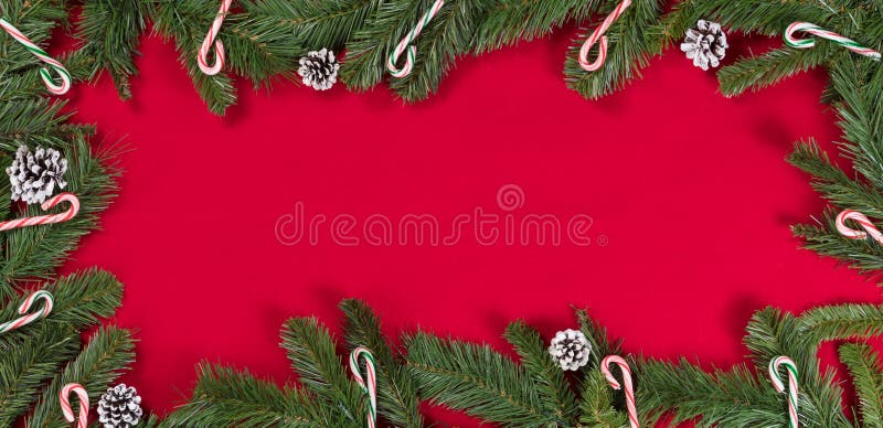 Evergreen Branches and Candy Canes Forming Border on Bright Red Stock ...