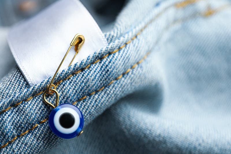 Evil Eye Safety Pin on Denim Clothing, Closeup Stock Image - Image of ...
