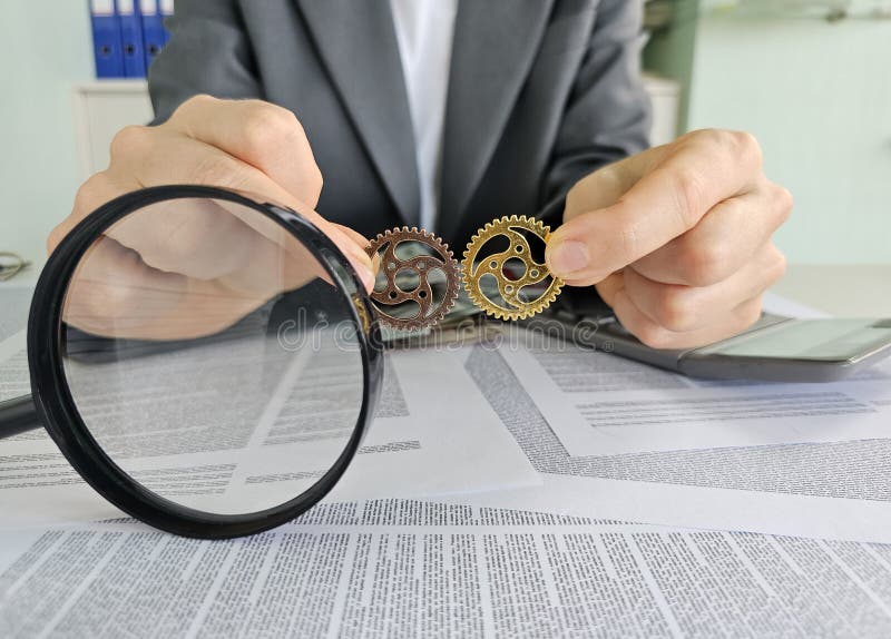 Examining Mechanical Gears with a Magnifying Glass in a Modern Office ...