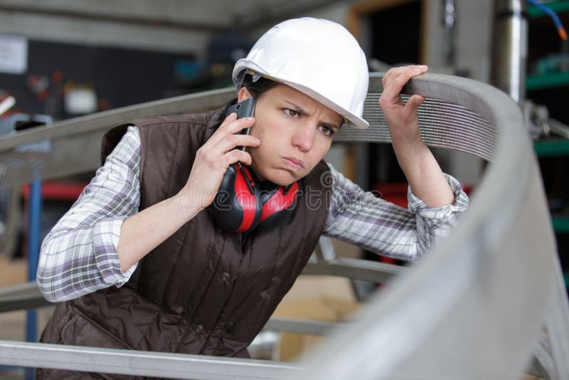 Exasperated Female Worker Using Smartphone in Factory Stock Photo ...