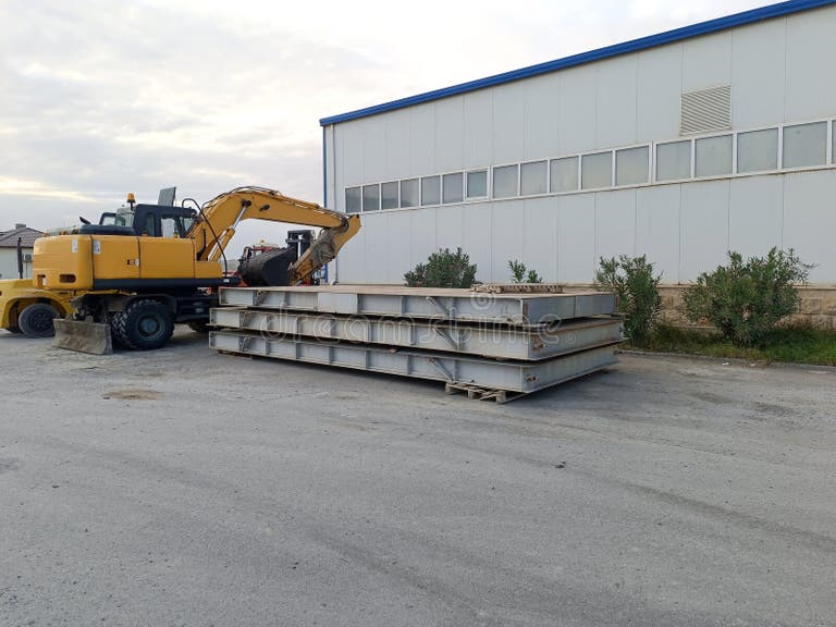An Excavator on a Break Near a Warehouse, Next To a Container Stock ...