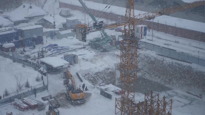 Excavator and a Crane Working on a Construction Site during a Snow ...