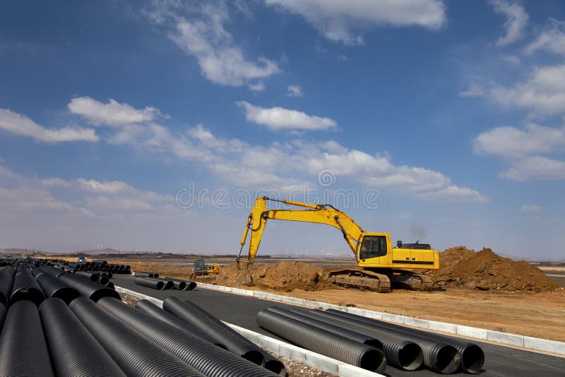 An Excavator is Digging a Ditch Alongside a Newly Built Road Stock ...