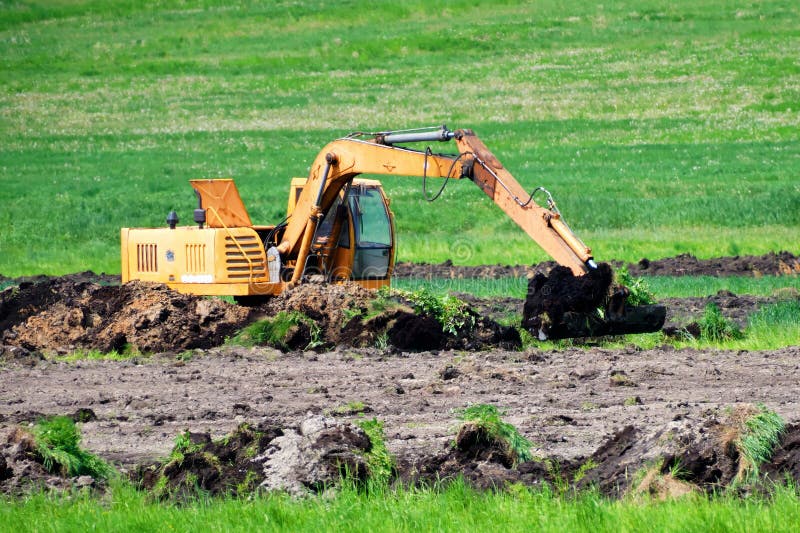 An Excavator is Digging the Ground. Construction Work on the Field of ...
