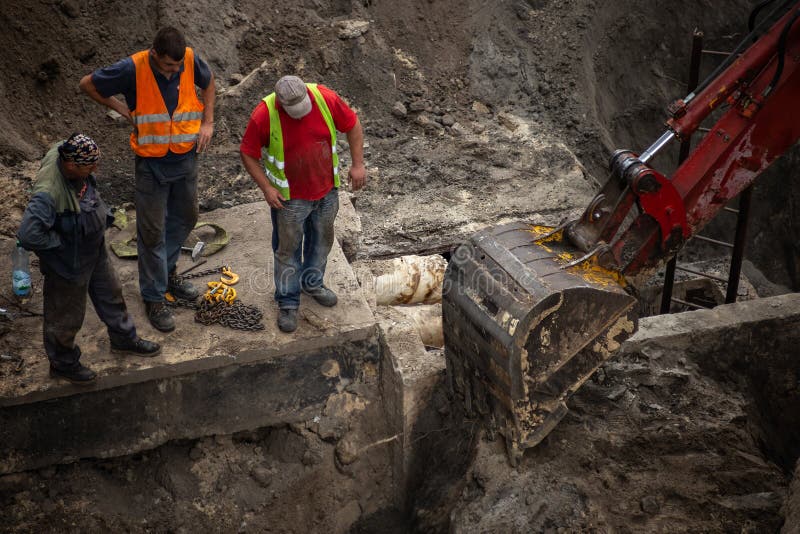 Excavator Digging a Pit. Three Workers Looking on Ladle Editorial ...