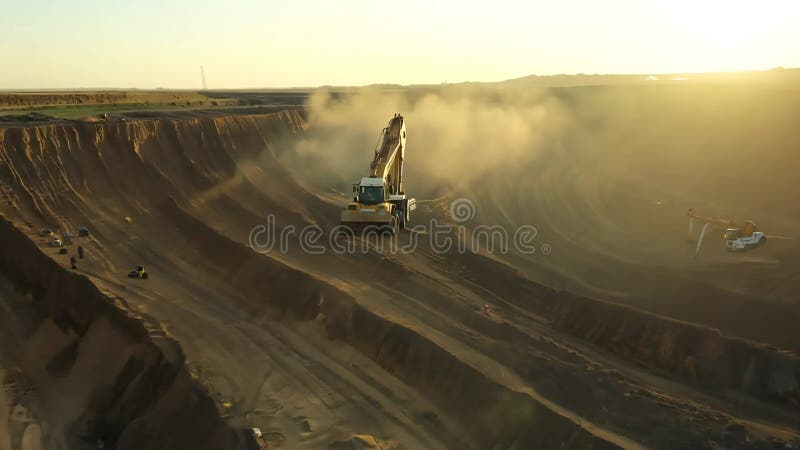 Excavator Digging in Vast Sand Quarry at Sunset, Creating Dust Clouds ...