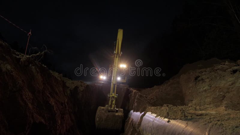 Excavator Digs a Trench with Headlights at Night. Work at Night. Night ...