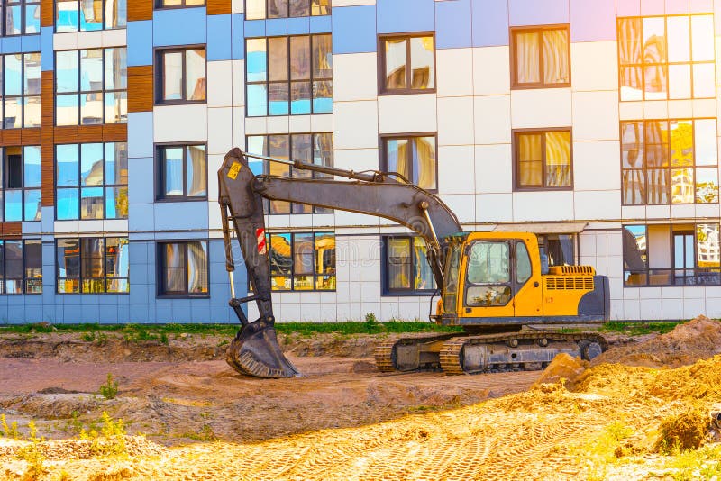 Excavator Equipment Against the Backdrop of a Multi-story Building ...