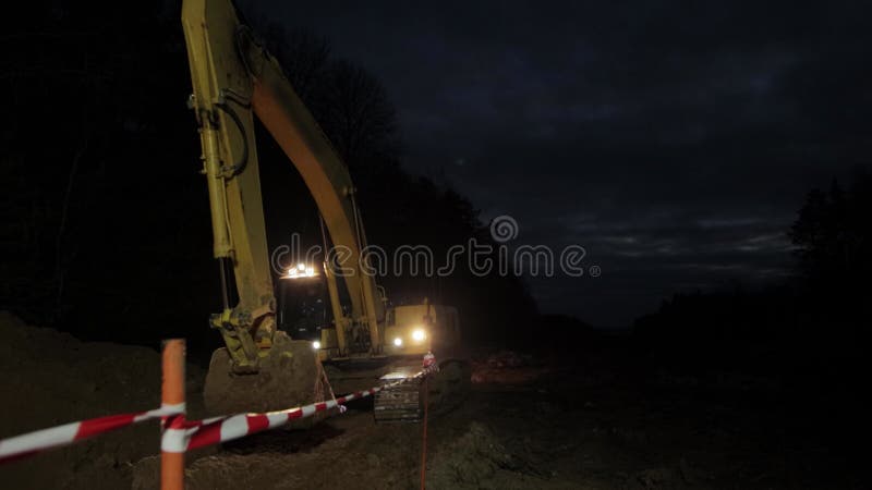 Excavator Digs a Trench with Headlights at Night. Work at Night. Night ...